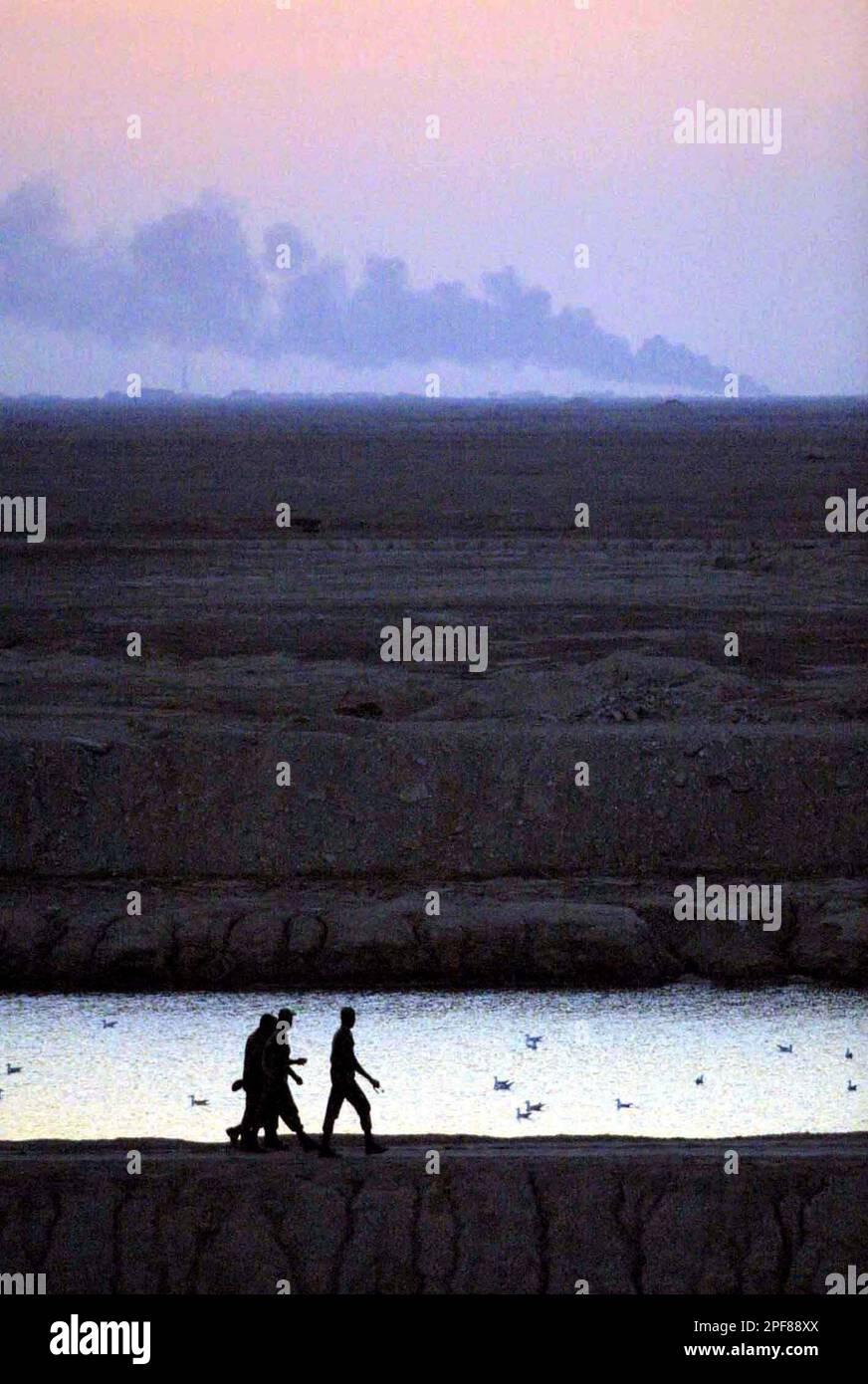 Iranian soldiers walk as smoke rises at sunset from Iraq's second ...