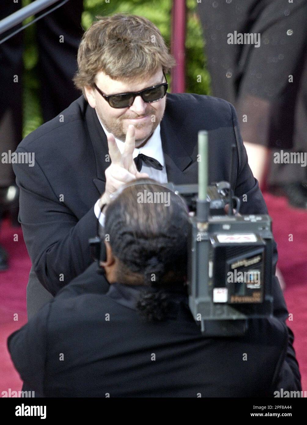 Michael Moore gives a cameraman a peace sign as he arrives for the 75th ...