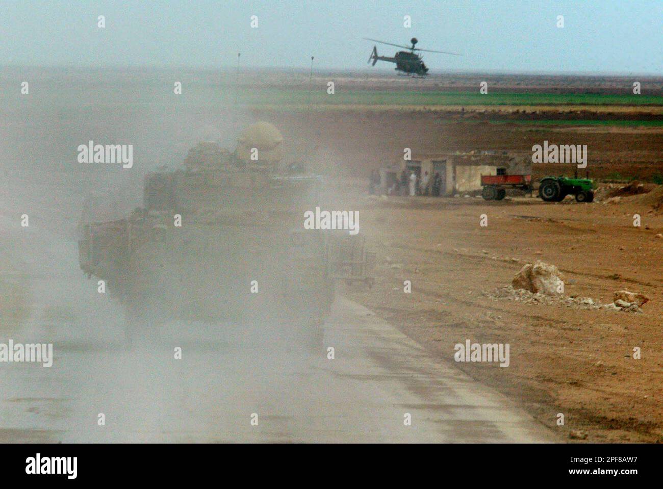 A U.S. Army convoy from the 3rd Infantry Division passes a small farm ...