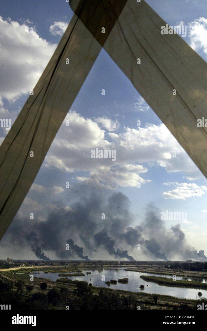 Columns of smoke, seen through a taped window, rise in the horizon of ...