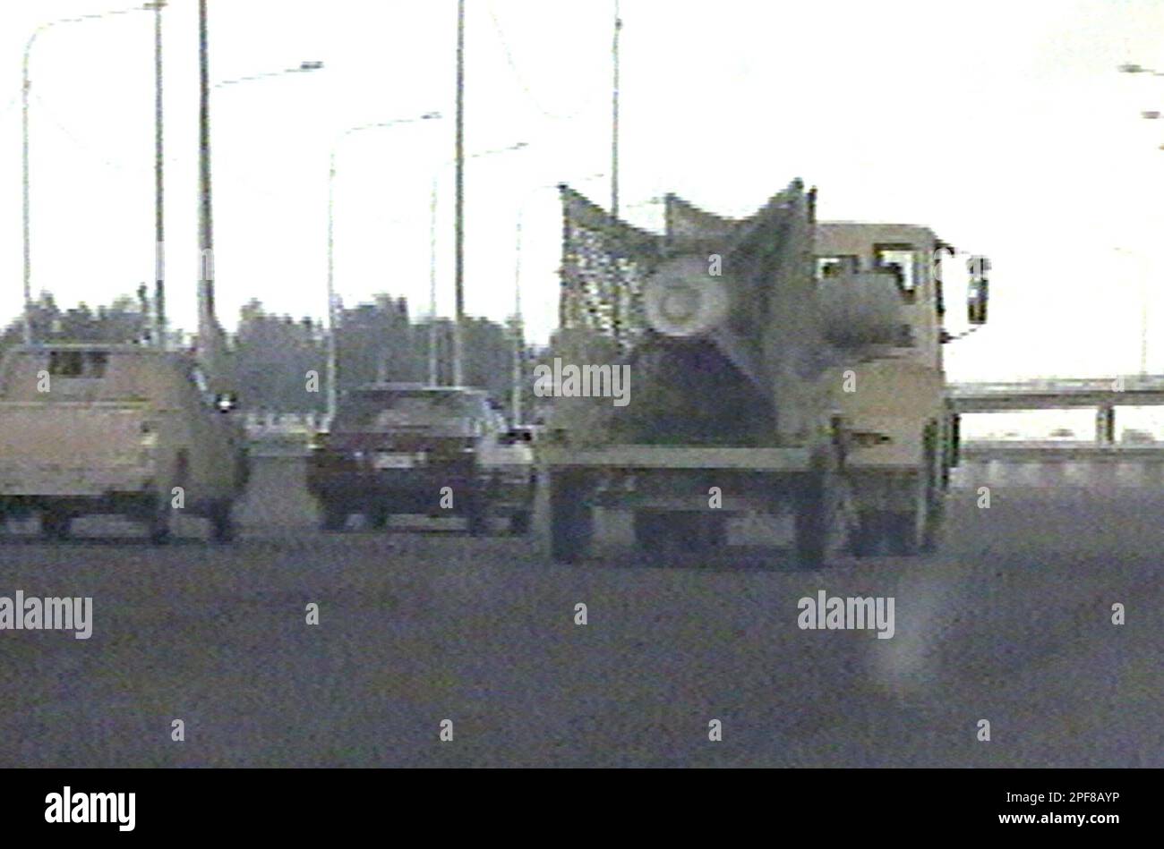 A large truck at right covered with camouflage netting carries what is ...