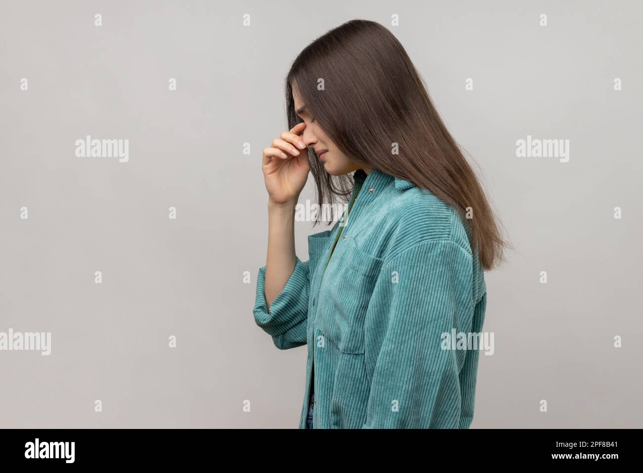 Side view of depressed woman holding her head down, touching face and ...