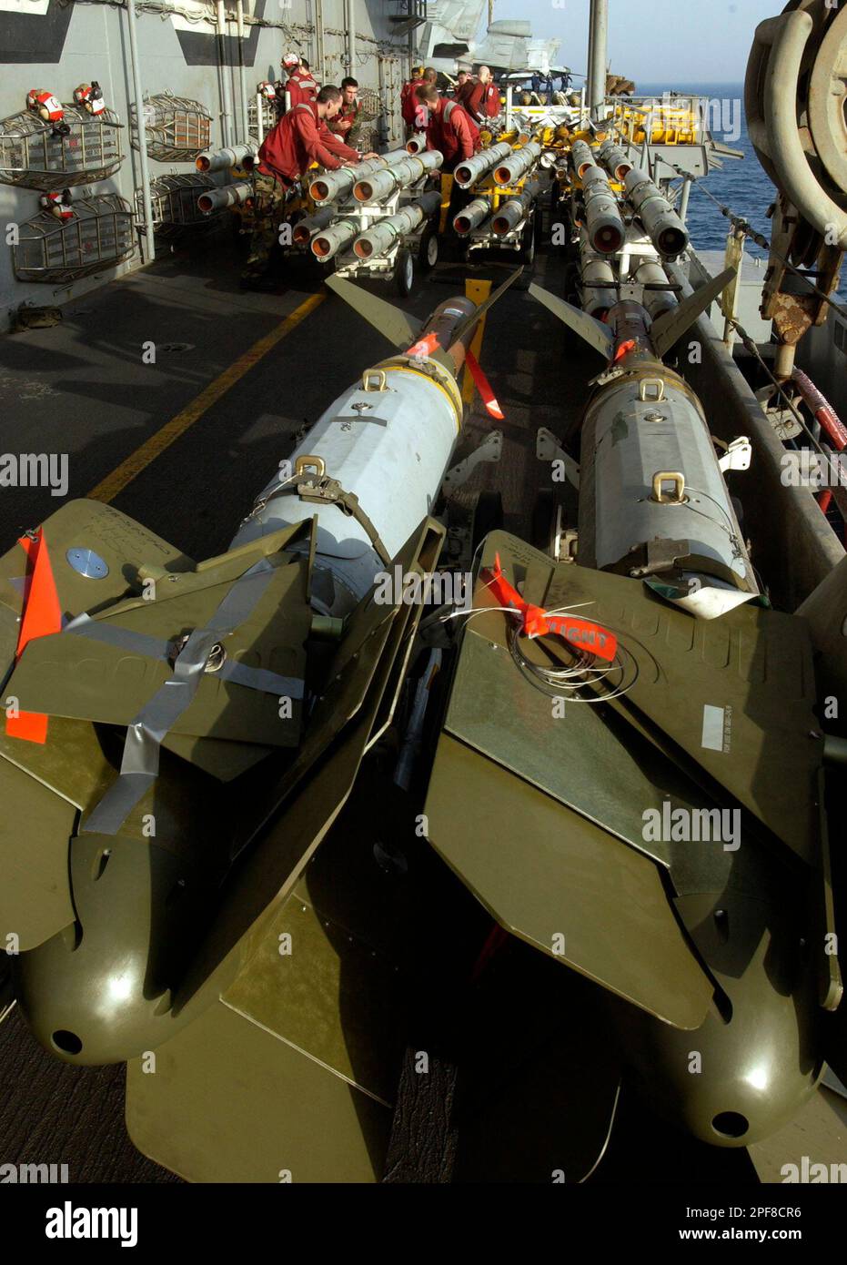Aviation ordnance specalists move missiles and bombs around a cluttered ...