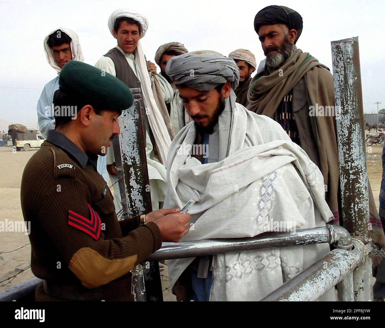 A Pakistani border guard checks ID cards of people entering into the ...