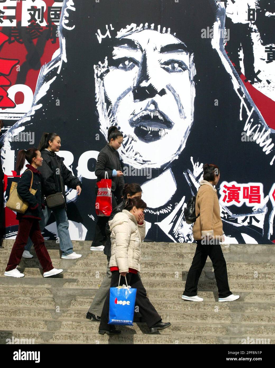Chinese walk past a billboard featuring Lei Feng, a model soldier and ...