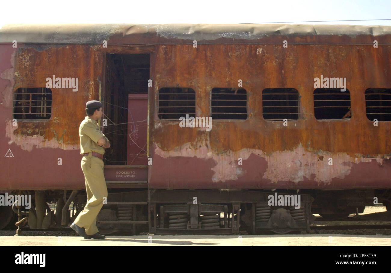 An unidentified policeman walks past the burnt S-6 coach of Sabarmati ...