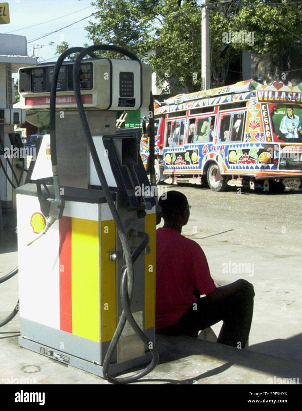 A Haitian driver waits for gas at a station whose pump nozzle dangles ...