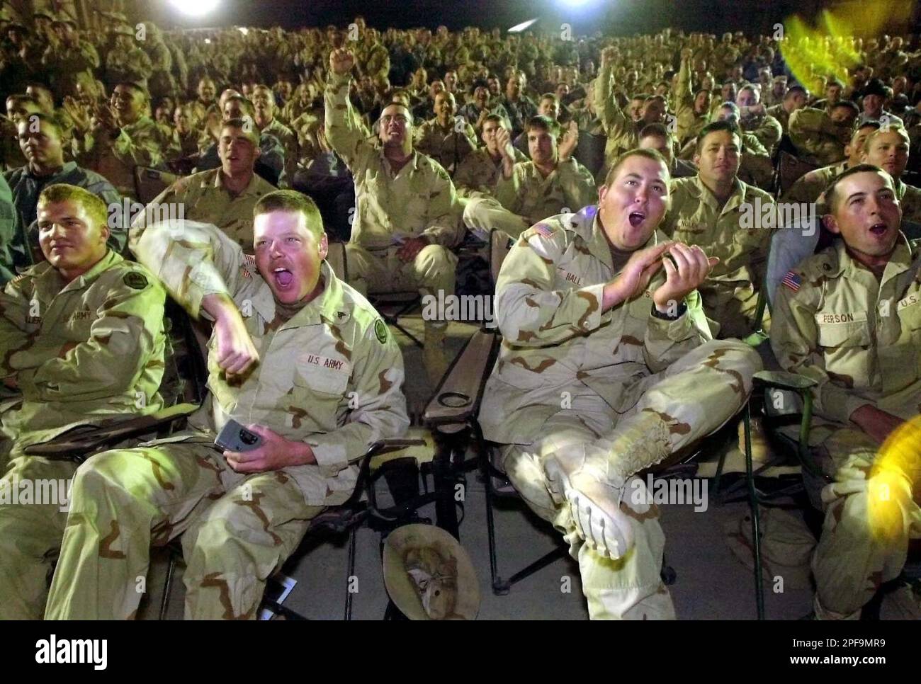 U.S. soldiers cheer an artist on a stage during the USO tour show at an ...