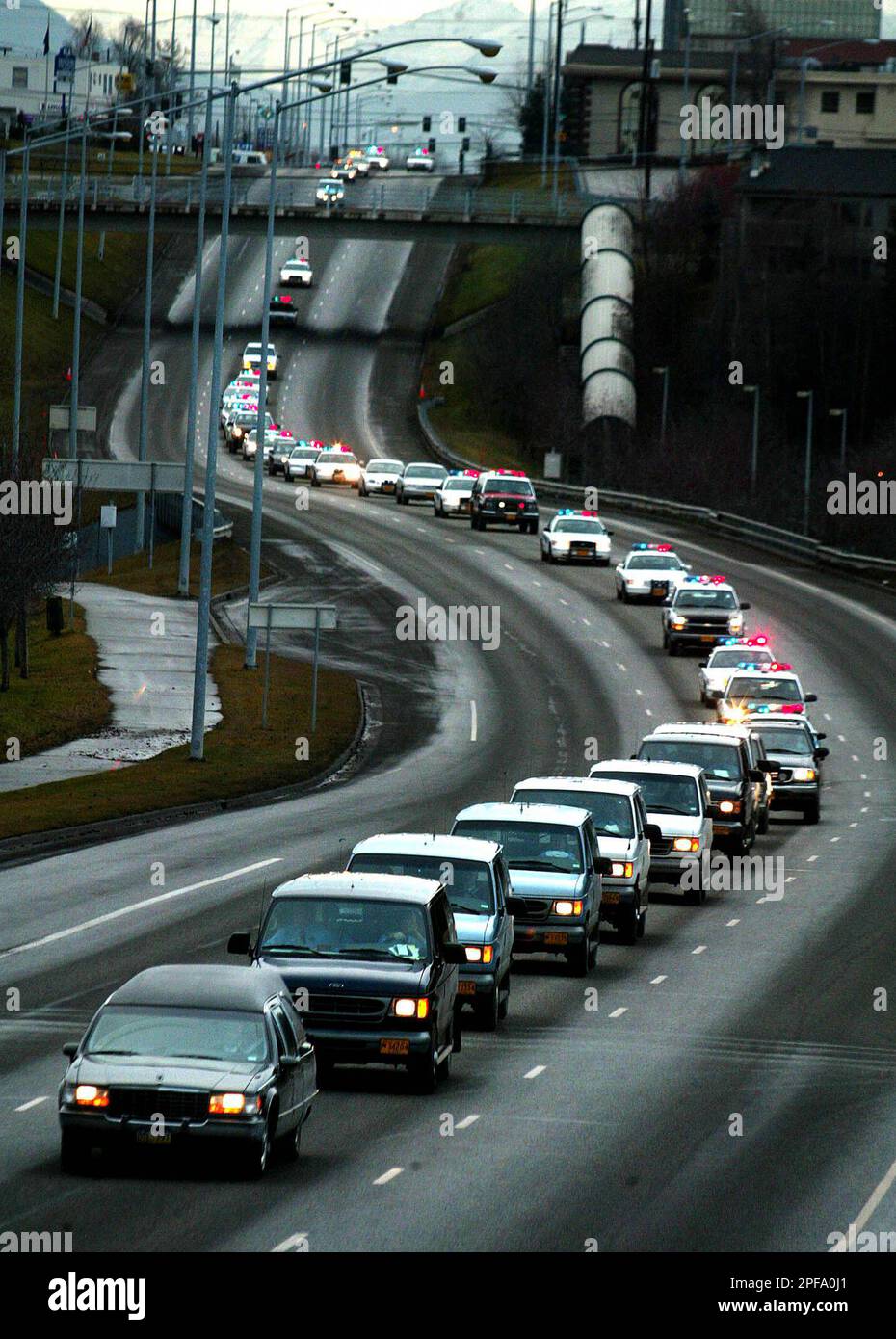 A procession of police cars follow the hearse carrying the body of ...