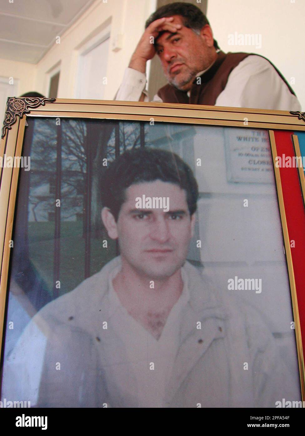 Nasibullah Khan Kasi sits behind his brother Aimal Kasi's photo at his ...