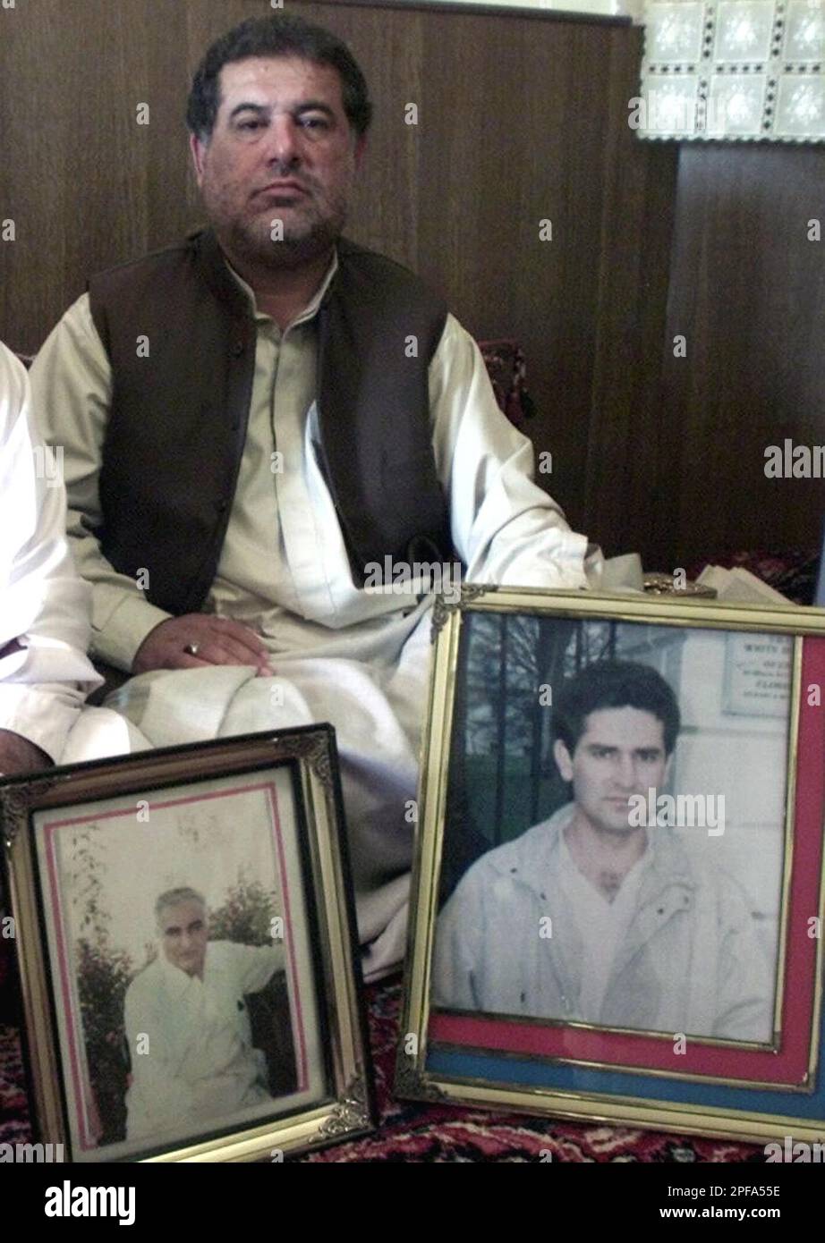 Nasibullah Khan Kasi, brother of Aimal Kasi, sits with photos of his ...