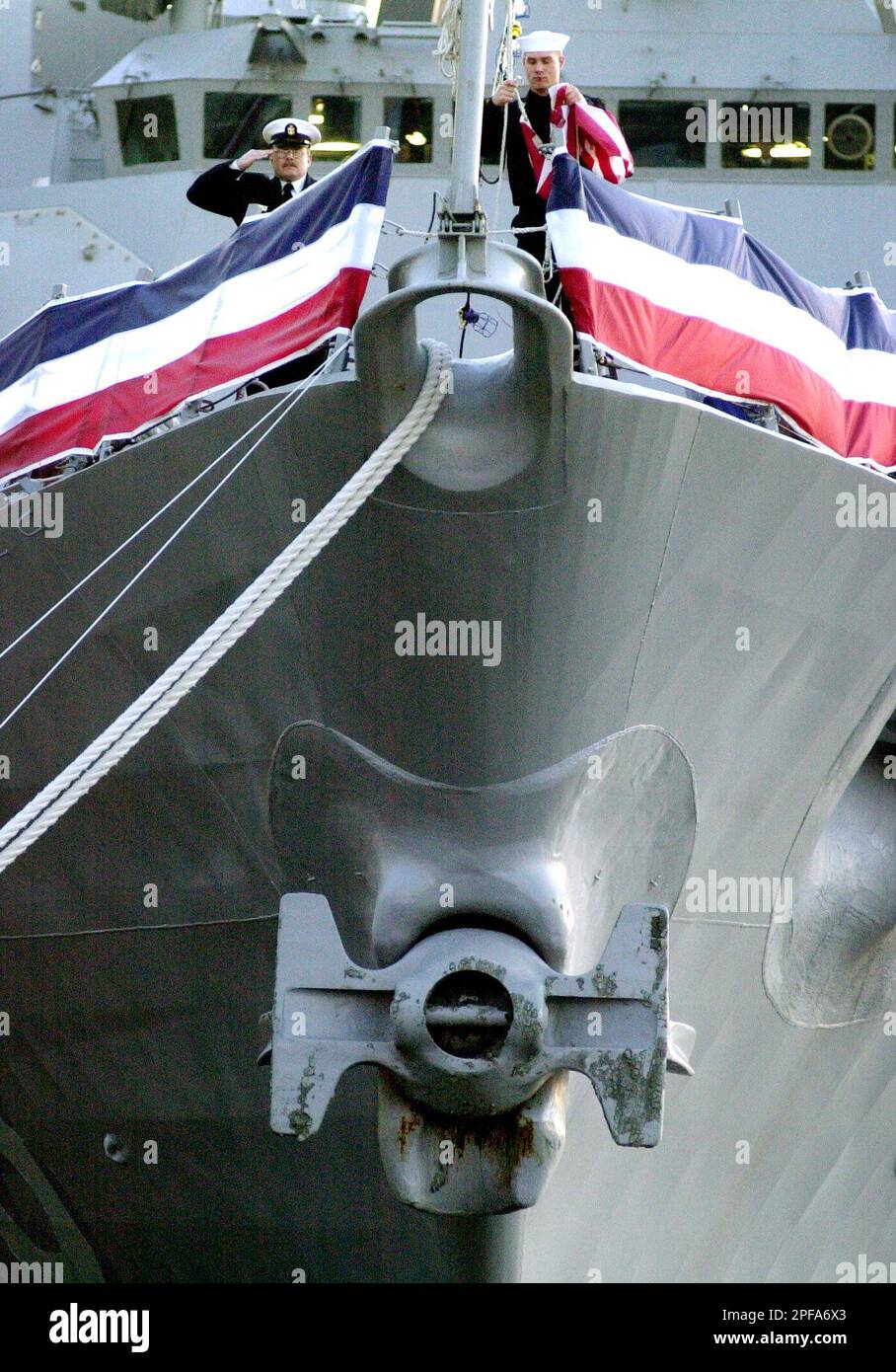 A U.S. Naval officer salutes as the U.S. flag is lowered at the bow of ...