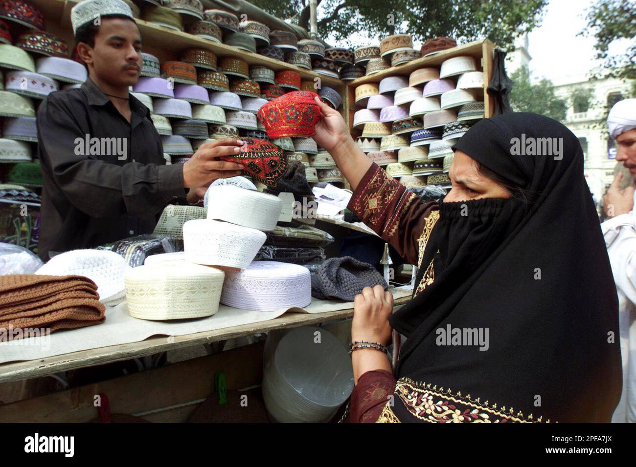 Pakistani woman buys a cap for her family members from a makeshift shop ...