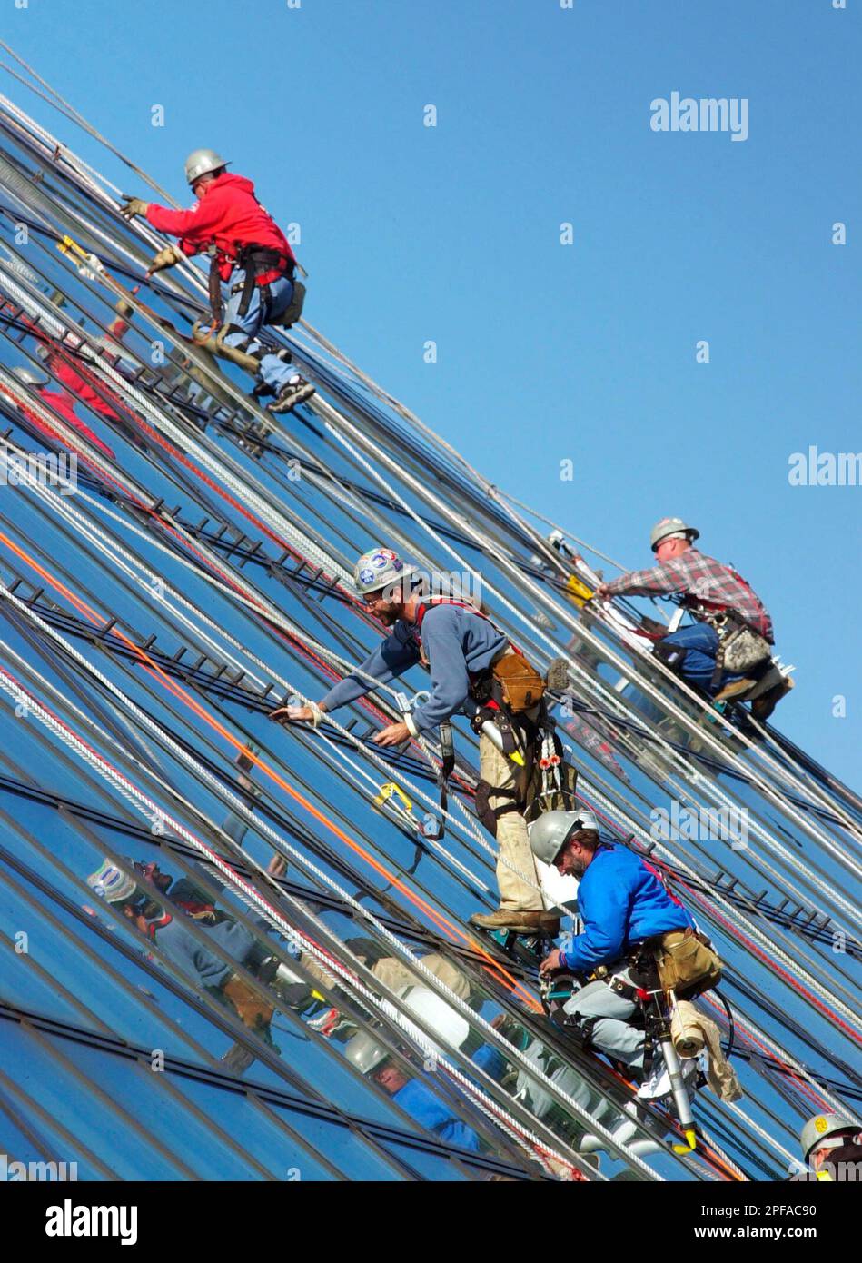 Workmen from Harmon Glass Co. scale the front of the Rock and Roll Hall ...