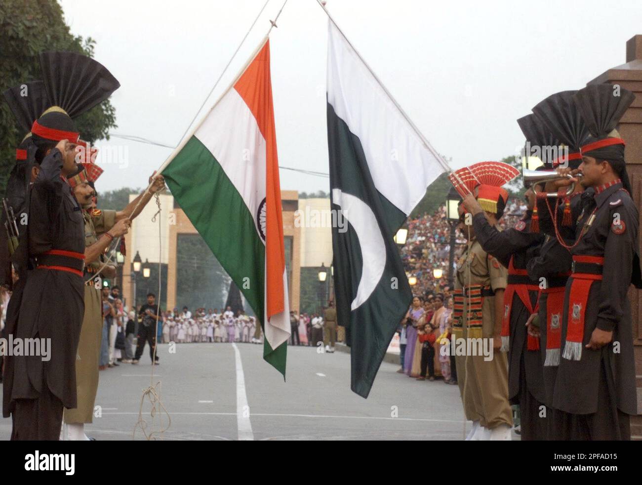 Pakistani border guards, right, and their Indian counterparts lower ...
