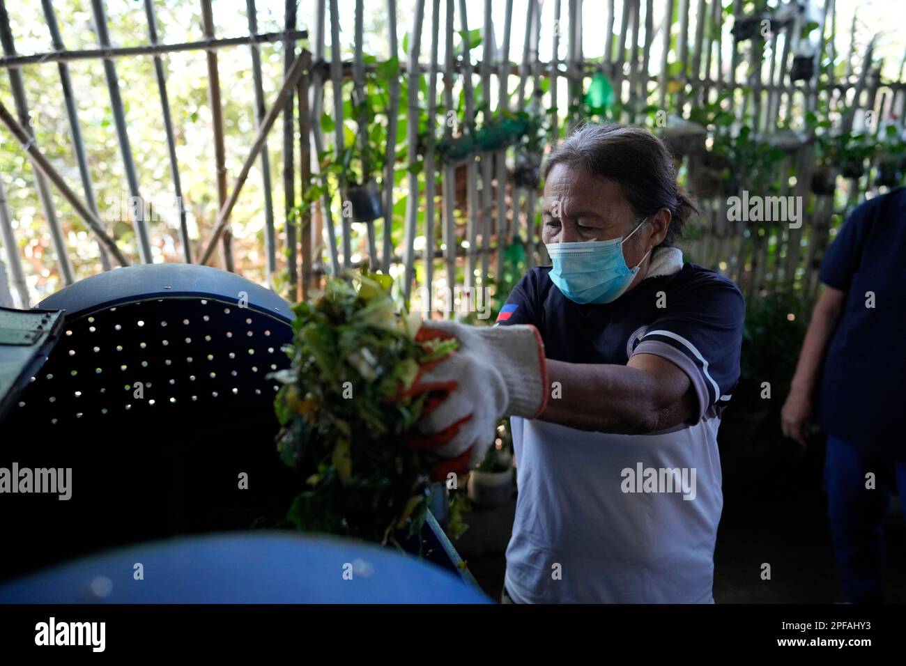A worker places organic waste for processing at a recycling facility in ...