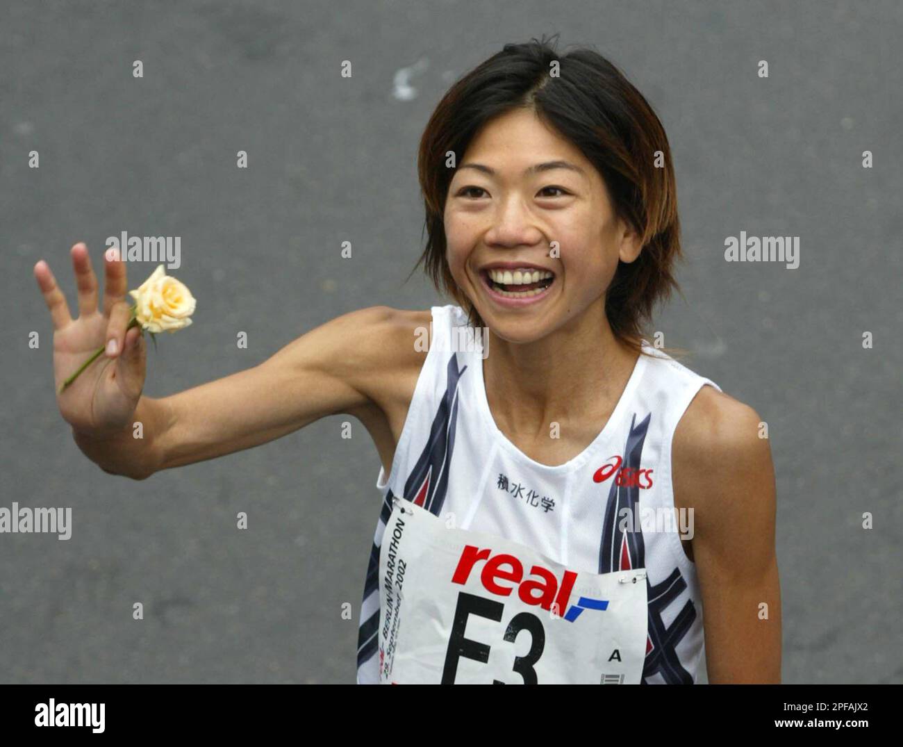Japan's Naoko Takahashi waves with a rose after she crossed the finish ...