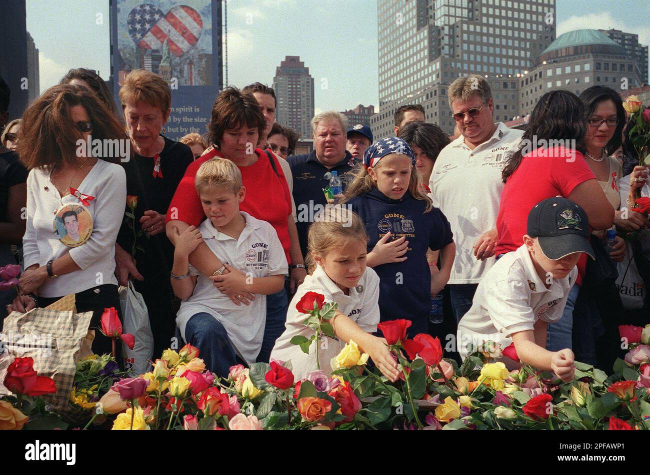 Children place flowers on a growing pile during a memorial service at ...