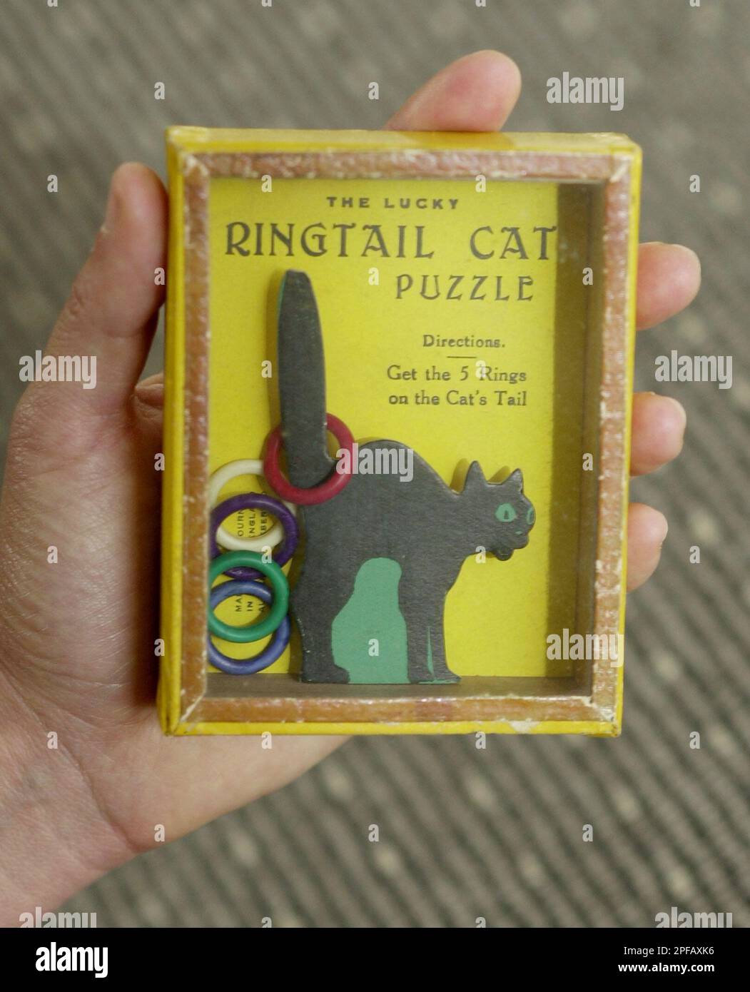 A person holds "The Lucky Ringtail Cat Puzzle" from 1930 that is as ...