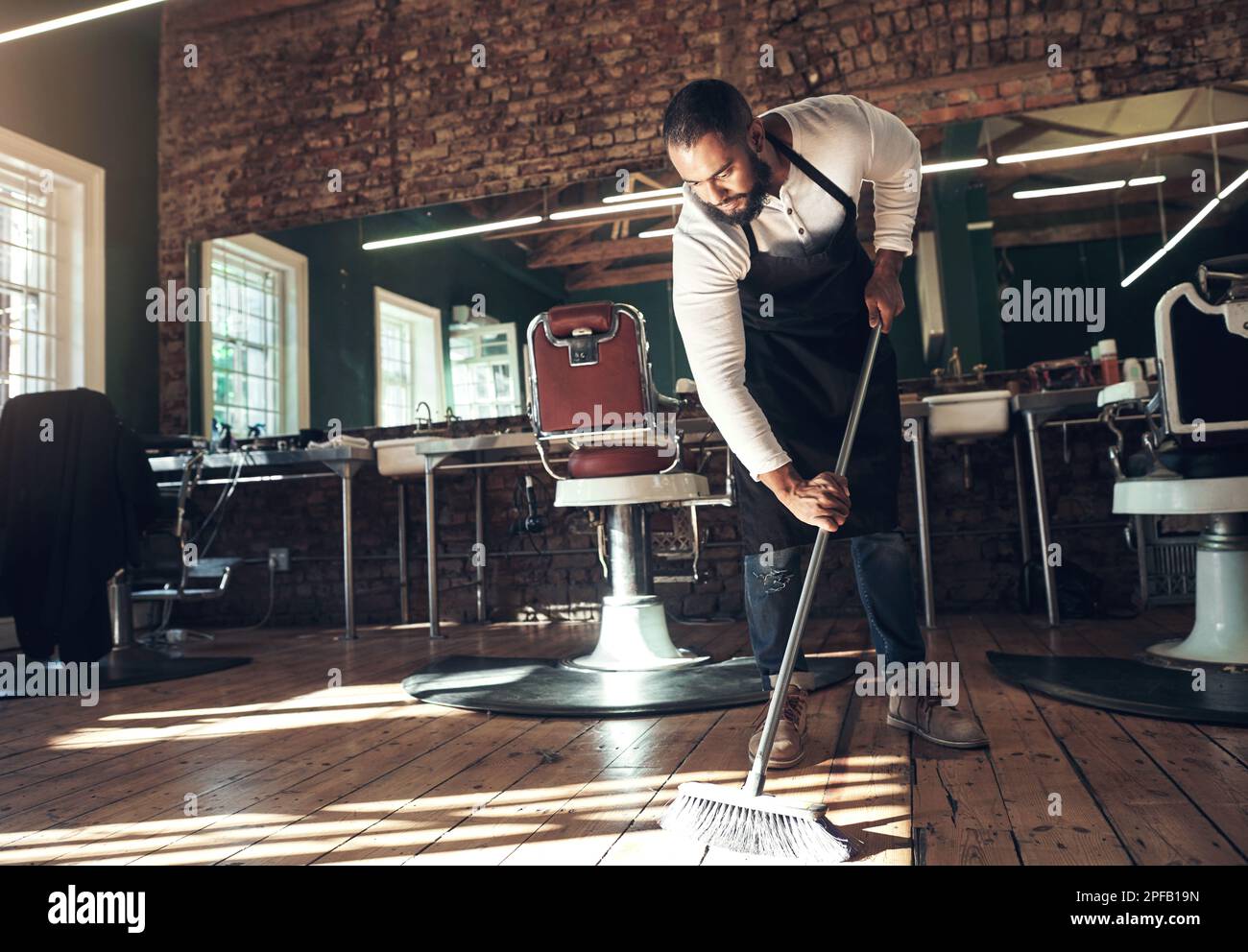 Young man sweeping hair salon hi-res stock photography and images - Alamy