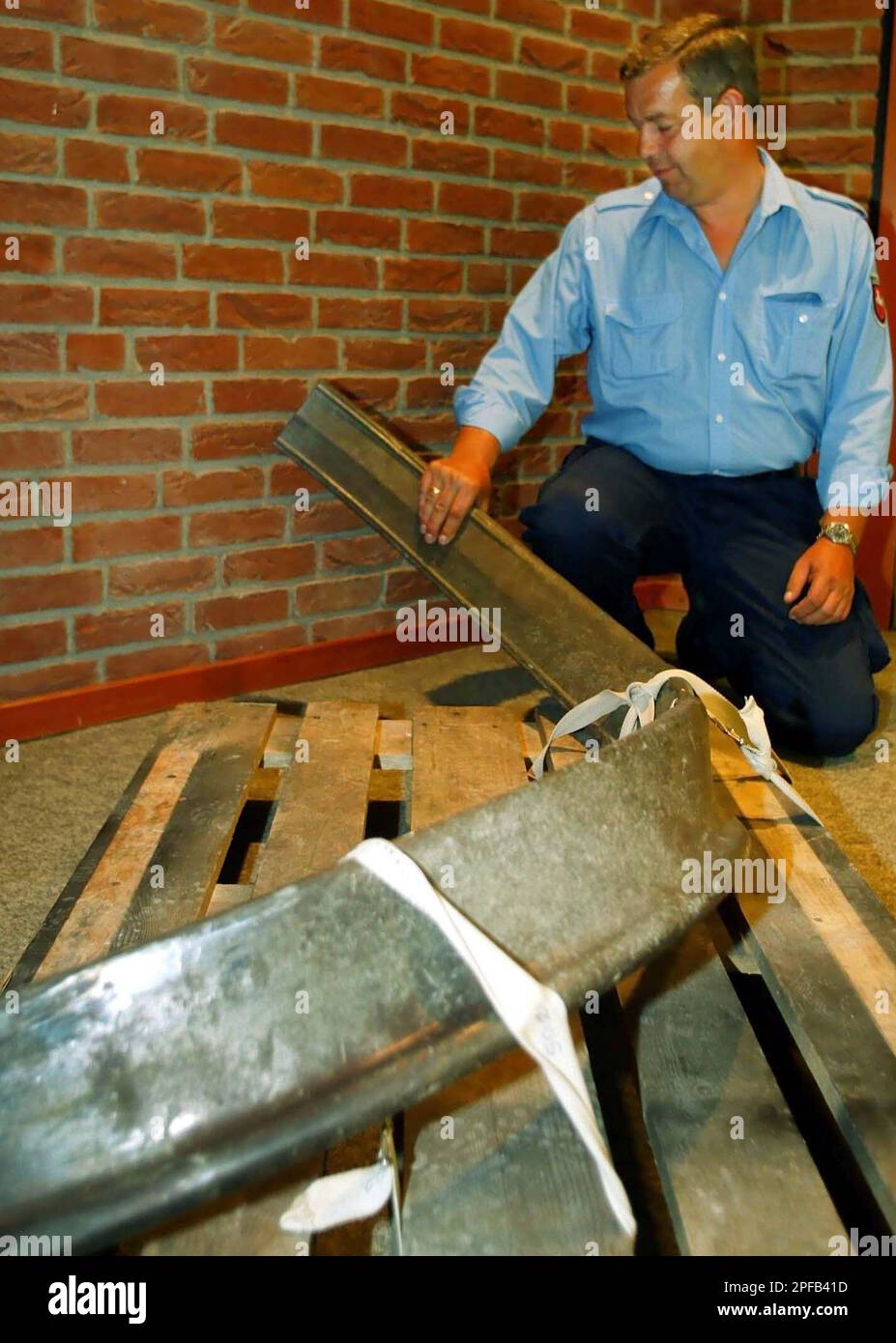 A justice official sits by a part of the broken wheel of the crashed ...