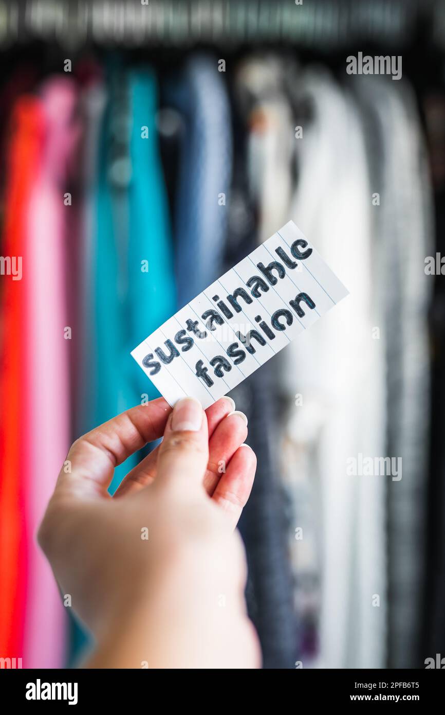 Sustainable Fashion held in front of wardrobe full of clothes, concept ...