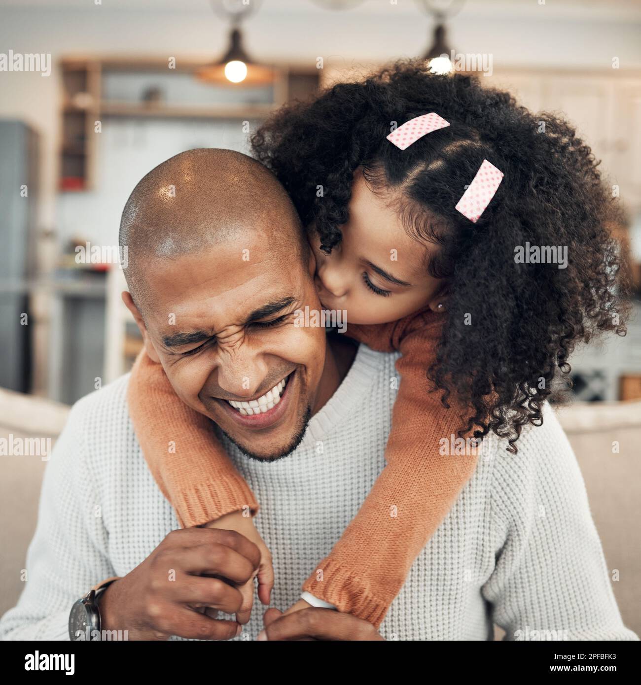 Family, hug and girl kissing father on sofa, happy and laugh, playing ...