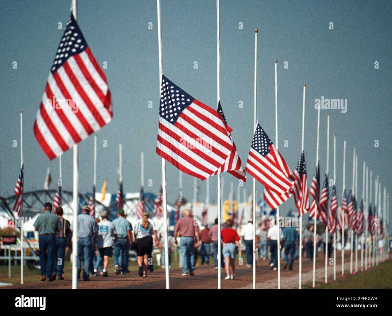 Visitors walk past flags at half-staff as they enter the grounds of ...