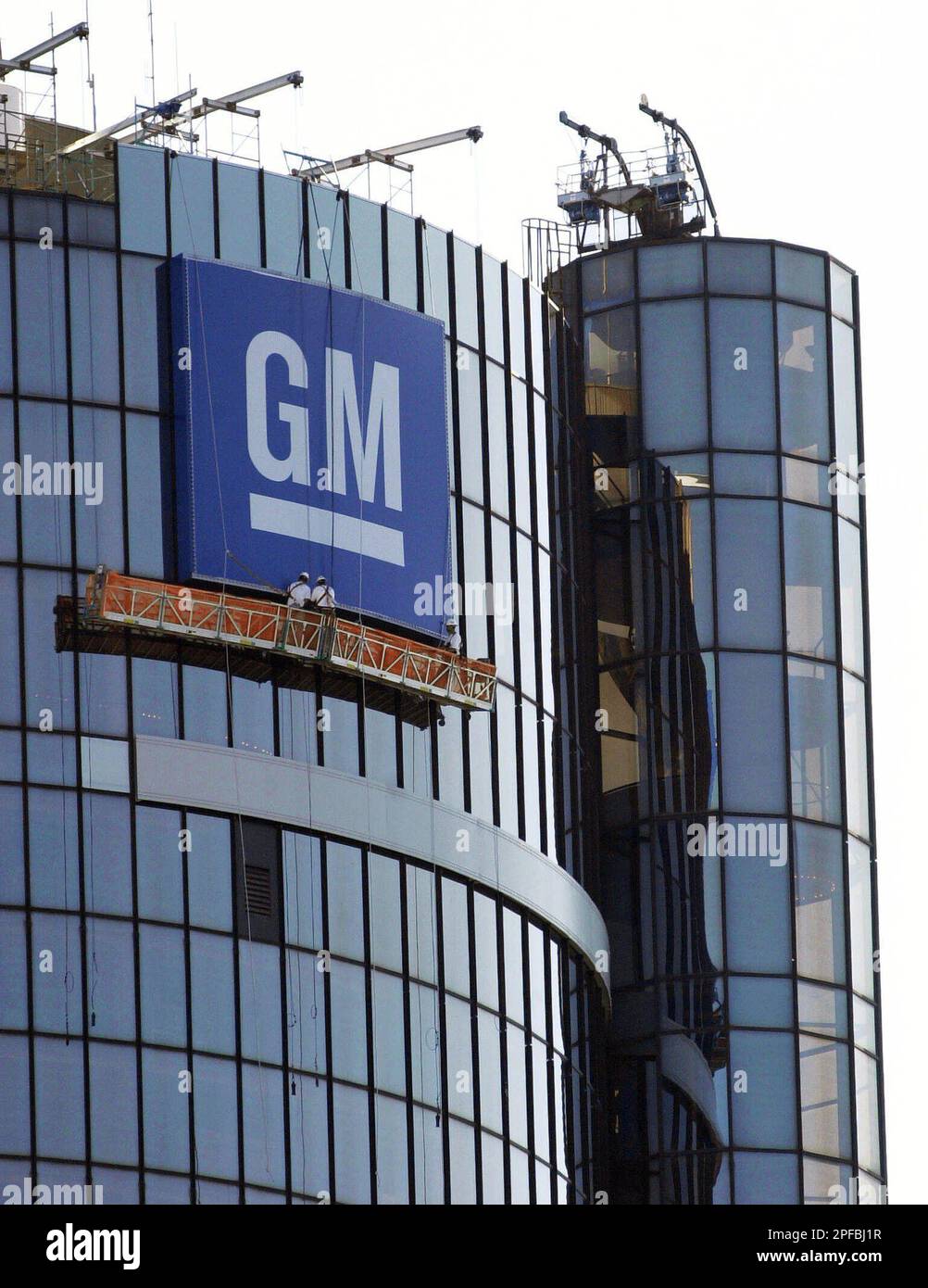 Workers attach a 25 by 25 foot General Motors logo atop the 740-foot ...