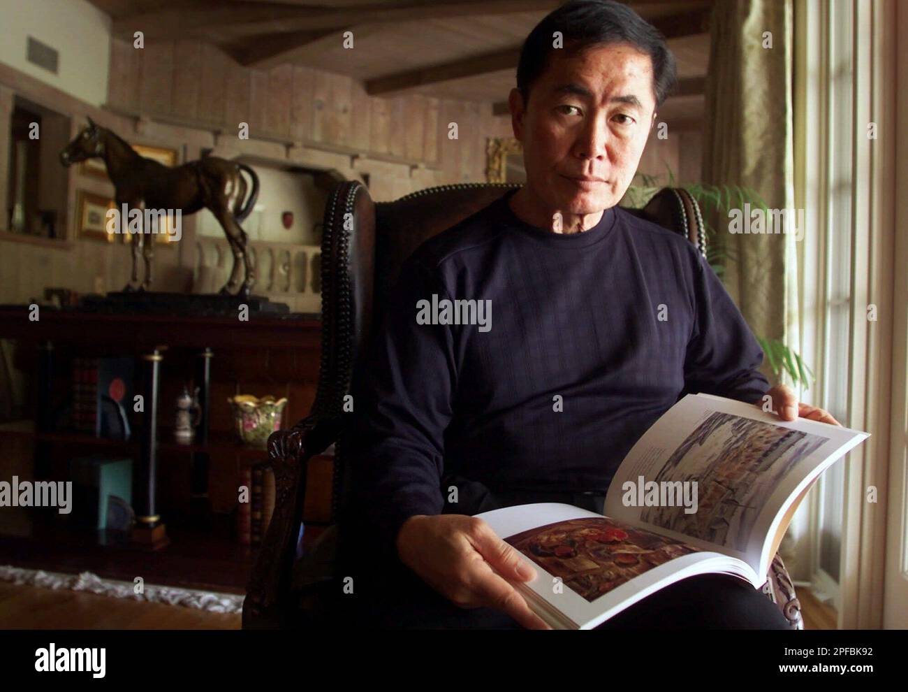 Actor George Takei looks at a book showing paintings of the Tule Lake ...