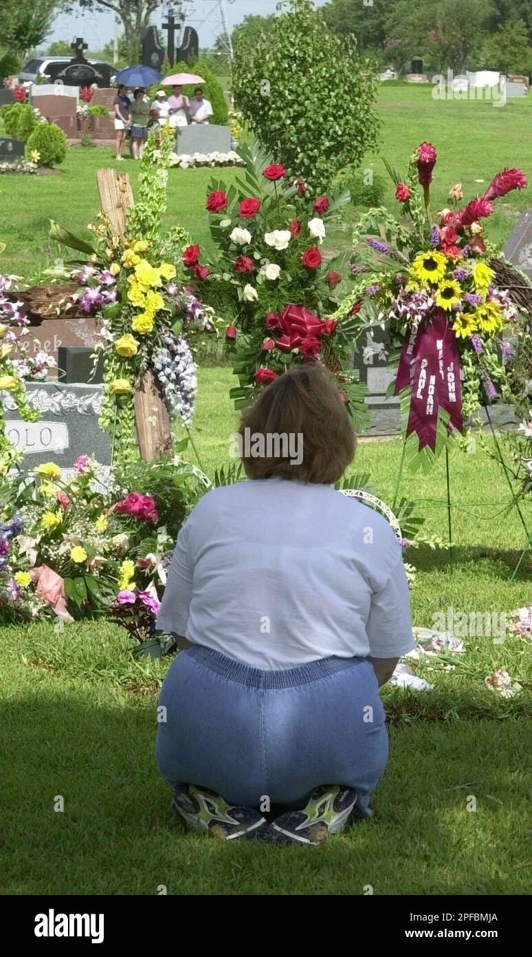 Debi Foreman kneels to pray at the graves of Noah, John, Paul, Luke and ...