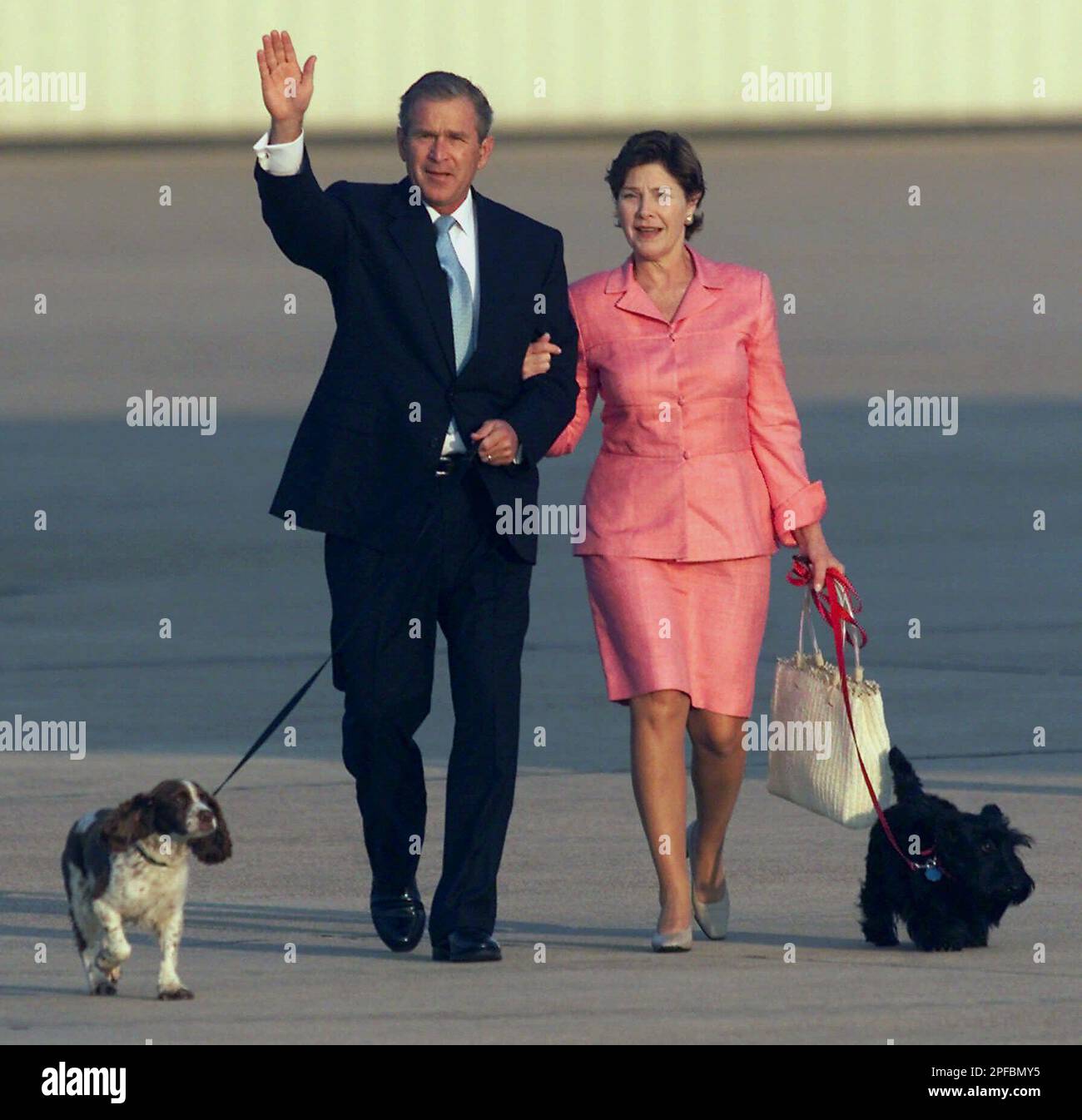 President Bush waves as he and first lady Laura Bush walk their dogs ...