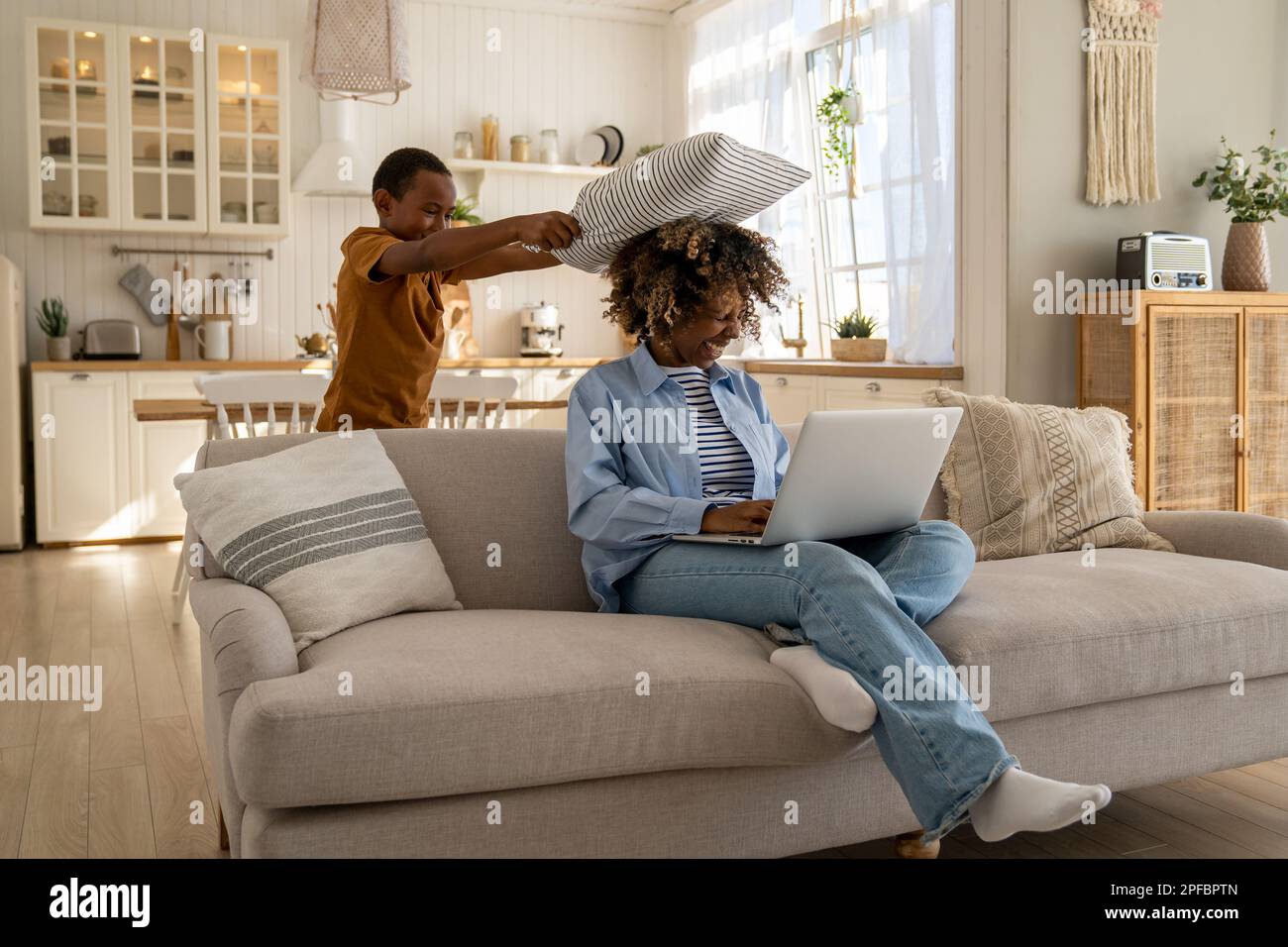 Content black child boy fun attack with pillow to busy smiling mom ...