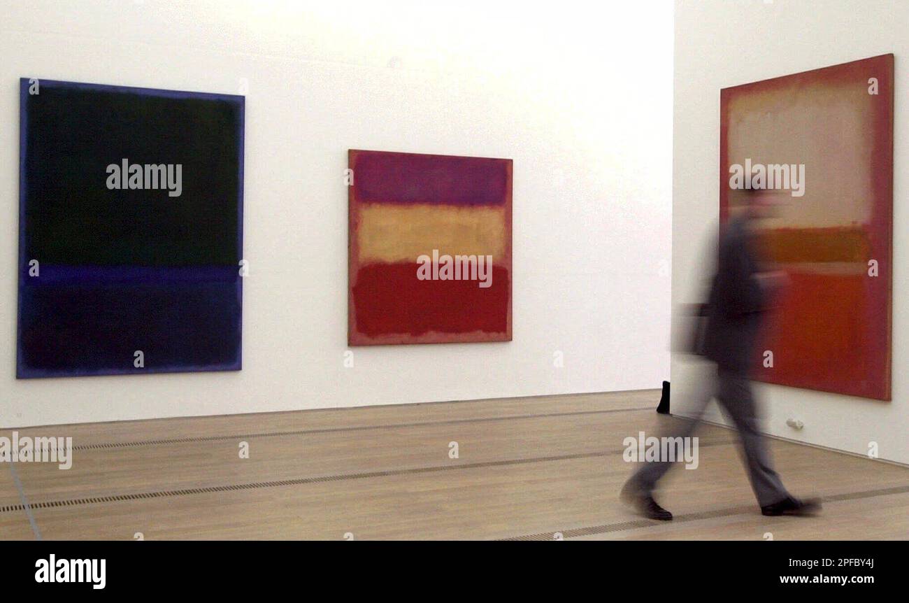 A visitor passes three paintings by Mark Rothko which are on exhibition ...