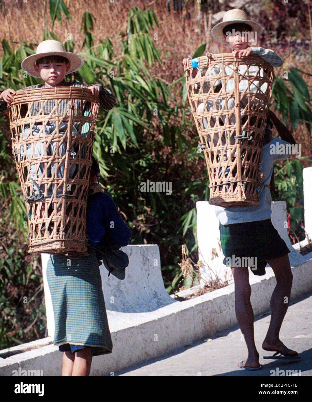 Two foreign tourists are carried in baskets on the backs of porters as ...
