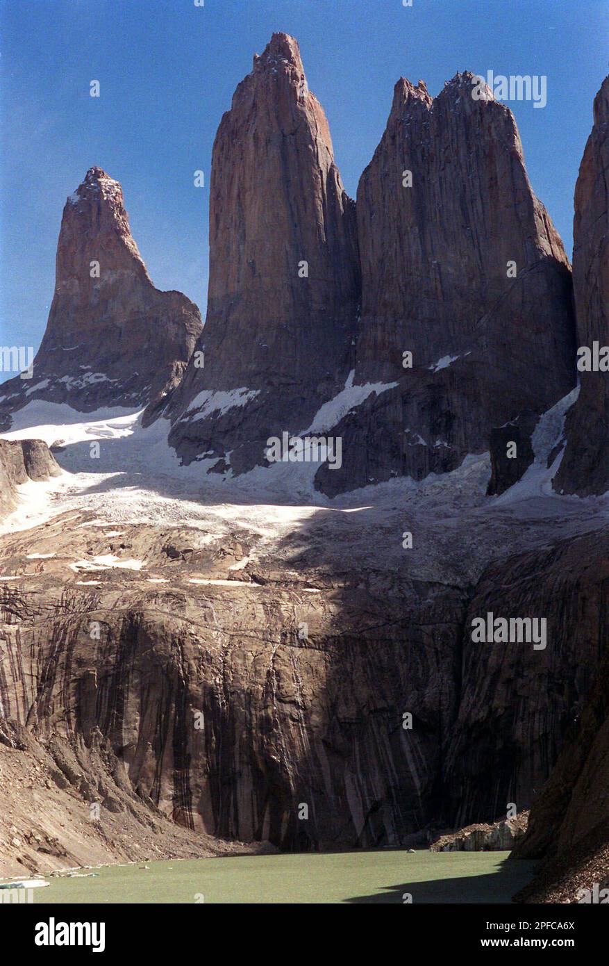 The peaks of Torres Del Paine loom in the clear blue skies of the ...