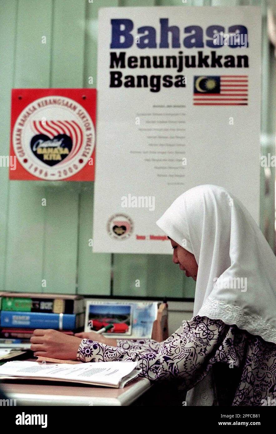 A Malaysian Muslim woman works in front of poster promoting the ...