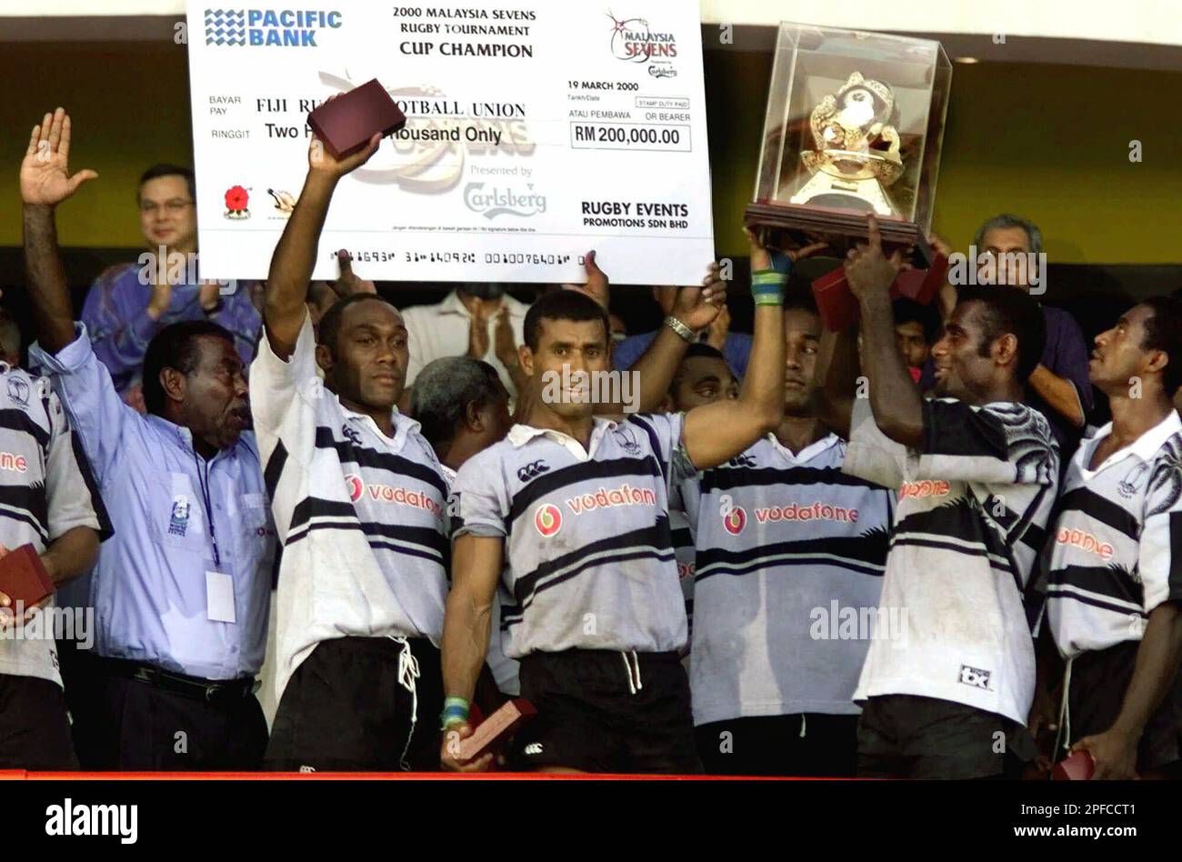Fiji's Waisele Serevi, center, representing the teams, holds up the winning trophy after they ...