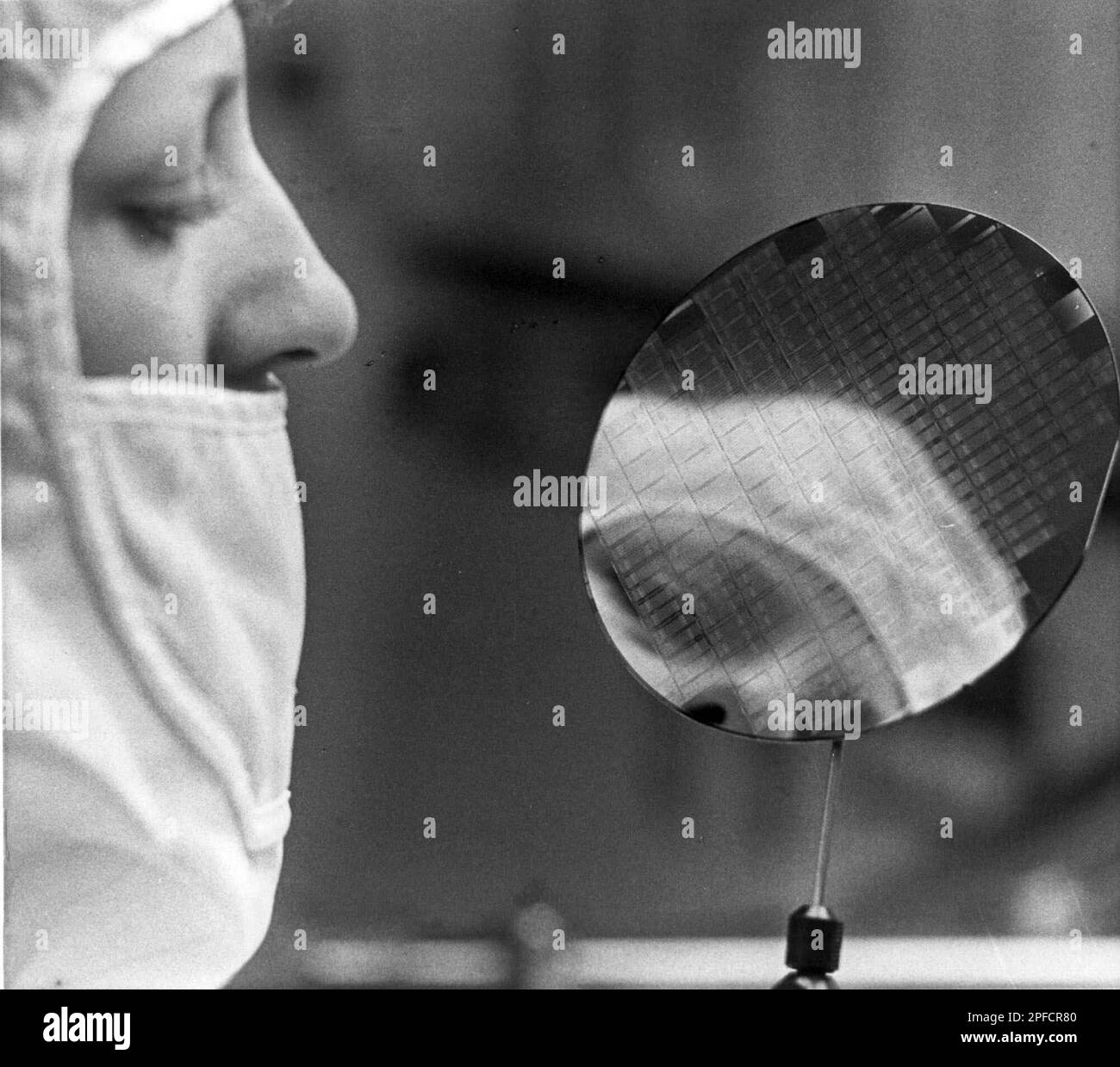 A worker checks a wafer of computer chips at the IBM manufacturing ...