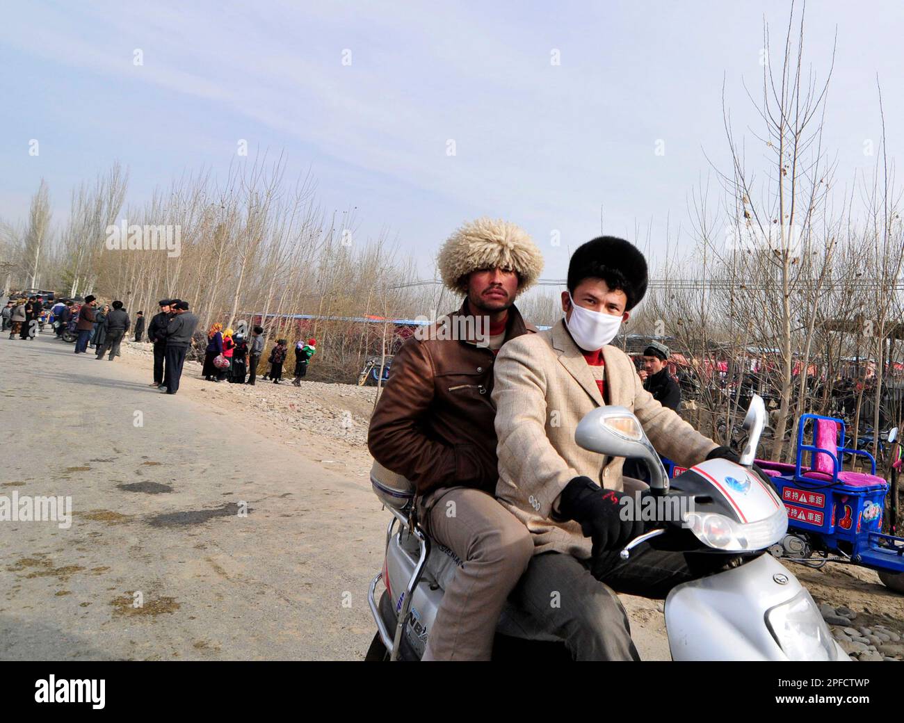 Uyghur men riding a scooter. Xinjiang, China Stock Photo - Alamy