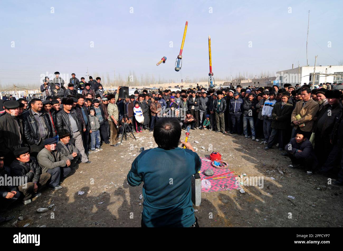 Uyghur men watching a show by a performer at a local weekly market in ...