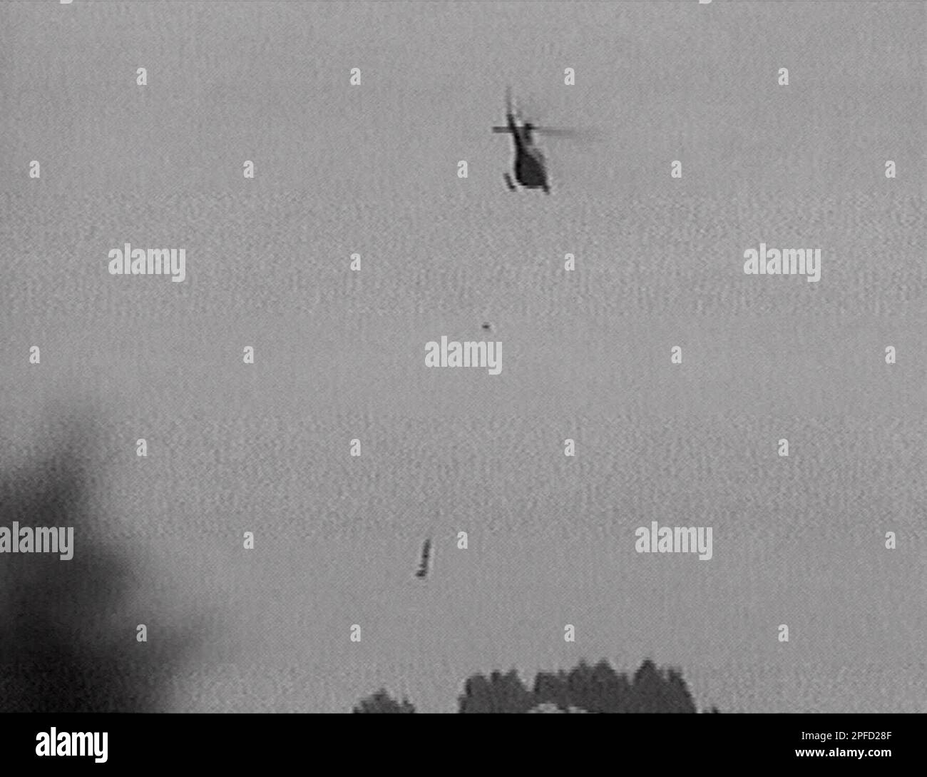 A helicopter carries a prisoner, dangling from a rope, whisked from a ...