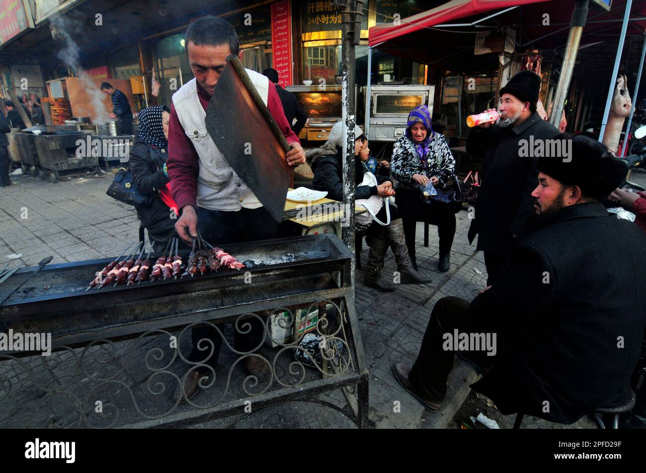 An Uyghur man grilling kebabs ( meat skewers ) in the old city of ...