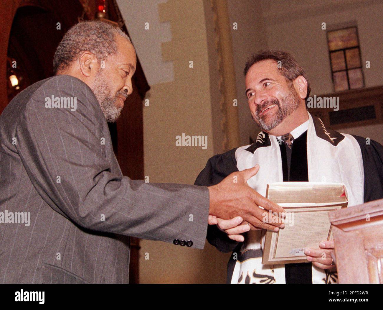 Rabbi Jaffrey A. Kahn, right, presents Imam W. Deen Mohammed, left, with a copy of the five ...