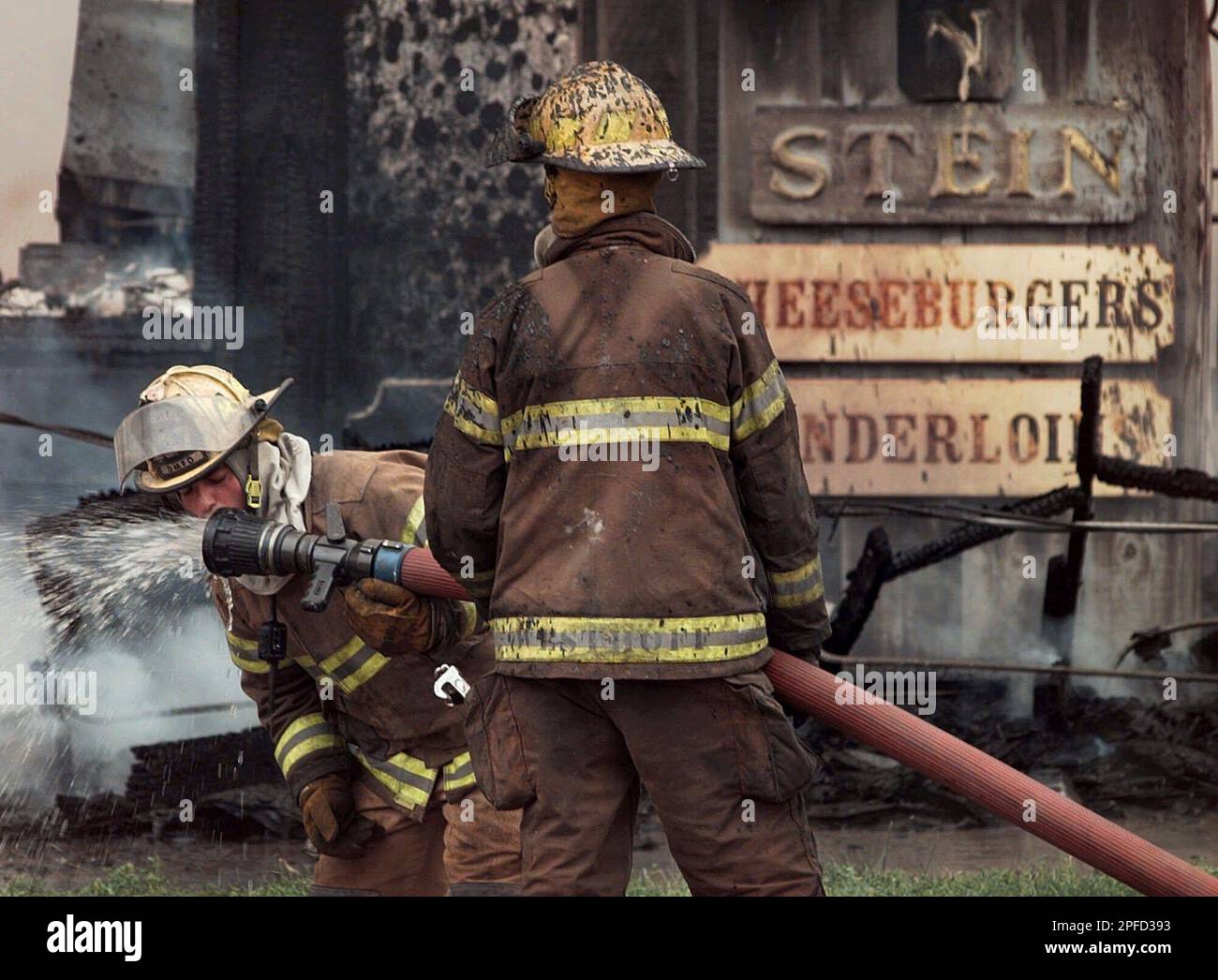 A firefighter takes a drink from a hose while battling a fire at the ...