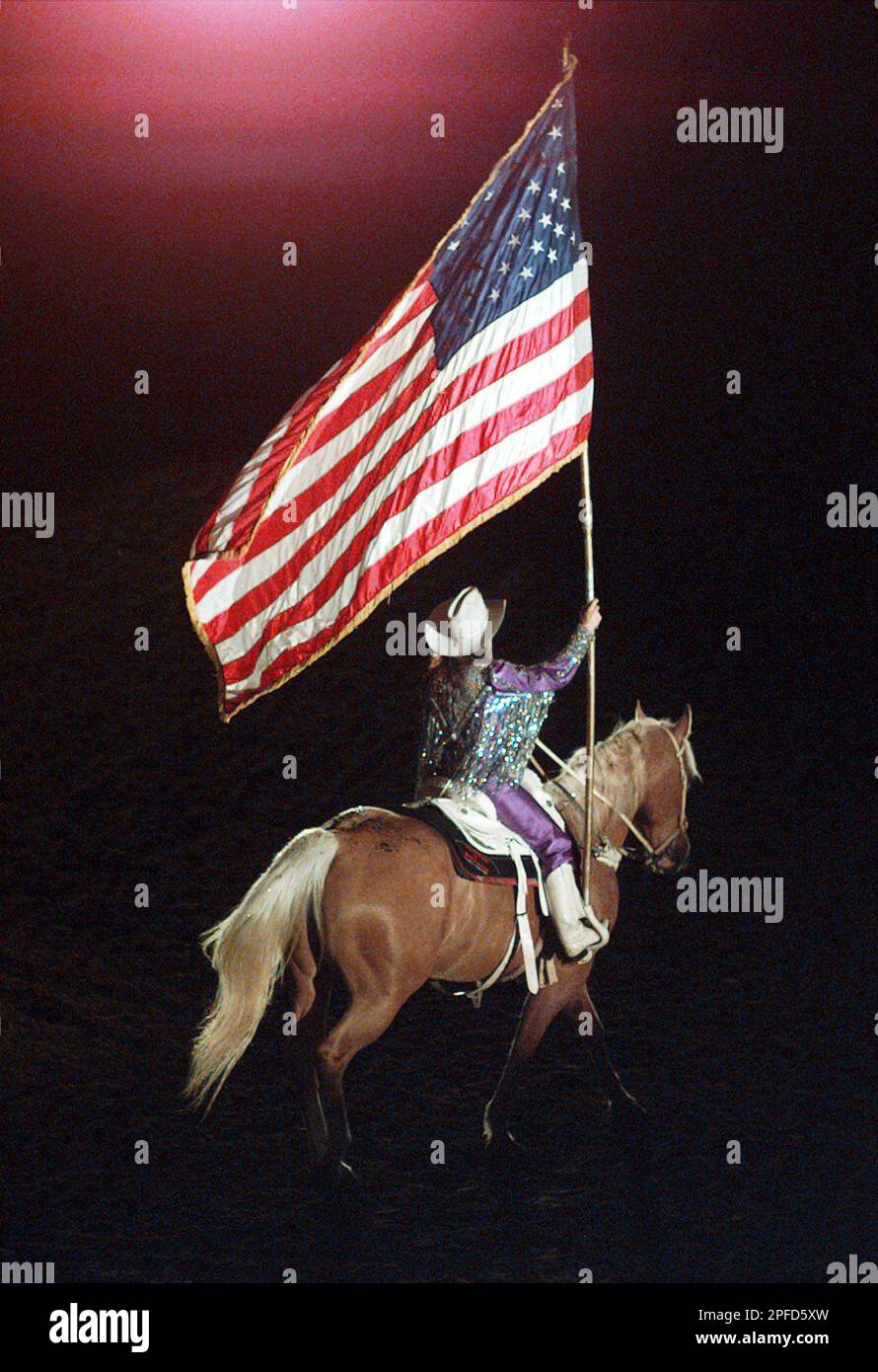 The American flag is paraded around the arena by a horseback rider ...