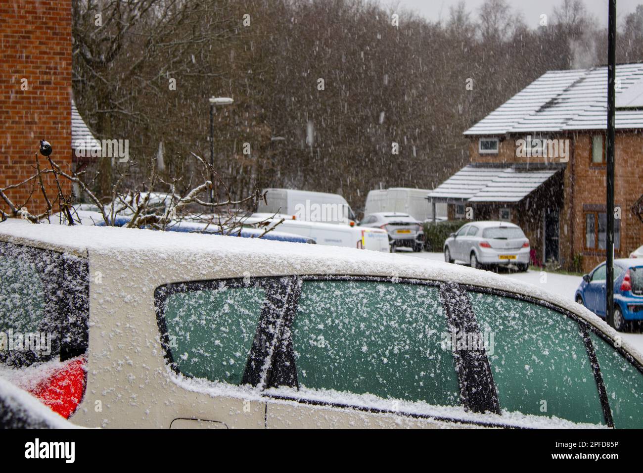 Snow falling on a car with a street scene behind Stock Photo - Alamy