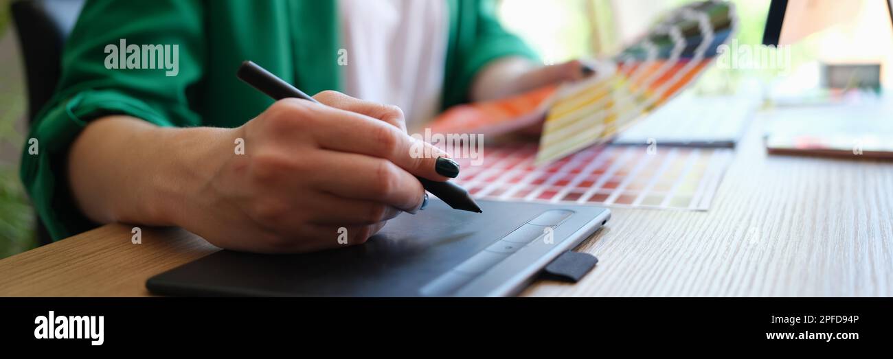Designer draws sketches on graphics tablet and holds color palette ...