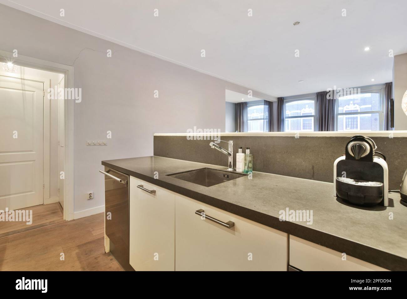 a kitchen area with white cabinets and black counter tops on the ...