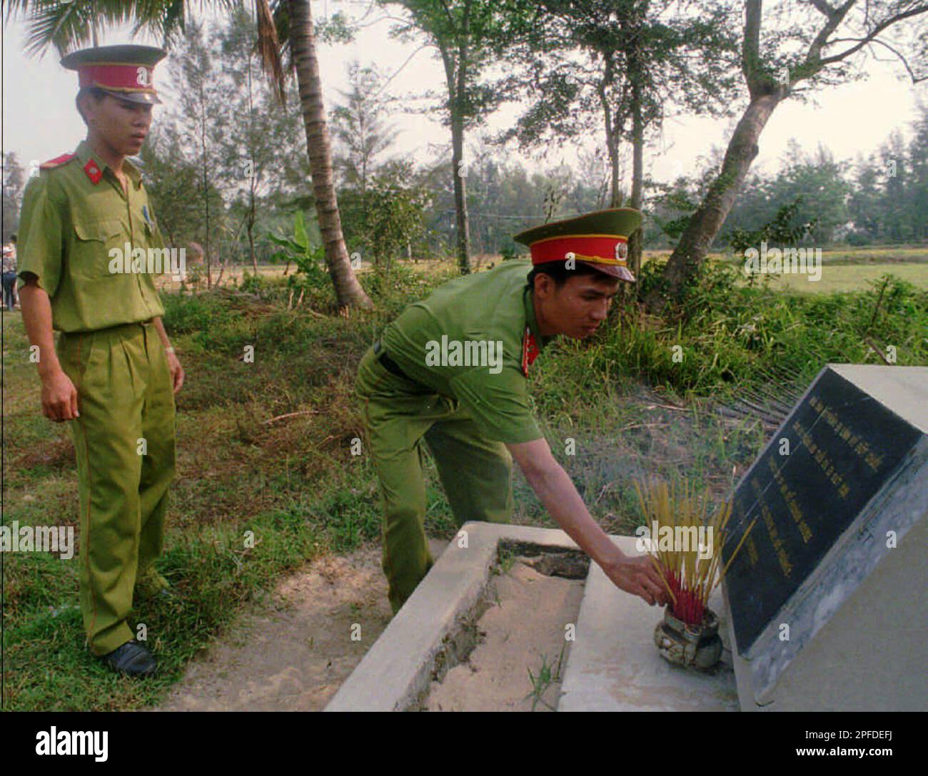 A young police officer puts joss sticks at a mass grave at the My Lai ...
